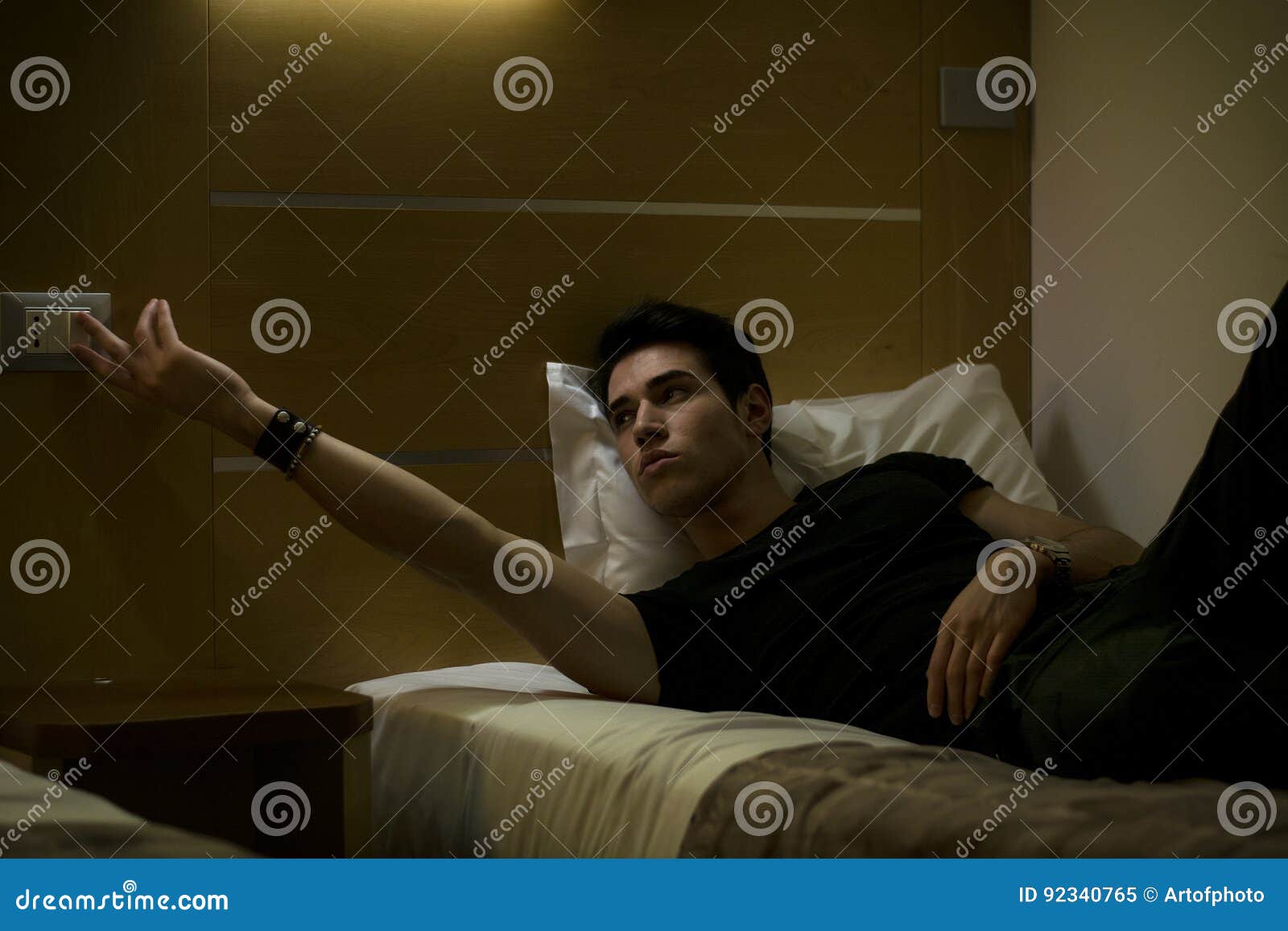 Guy Switching Cansado De La Luz Mientras Que Miente En Cama Imagen de ...