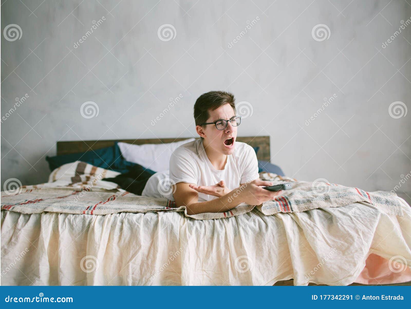 Guy Using Remote Control while Sitting on the Bed in Home. Happy ...
