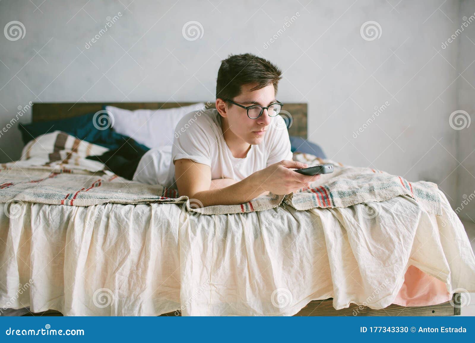 Guy Using Remote Control while Sitting on the Bed in Home. Happy ...