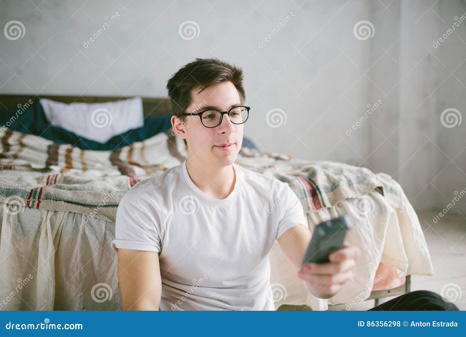 Guy Using Remote Control while Sitting on the Bed in Home. Happy ...