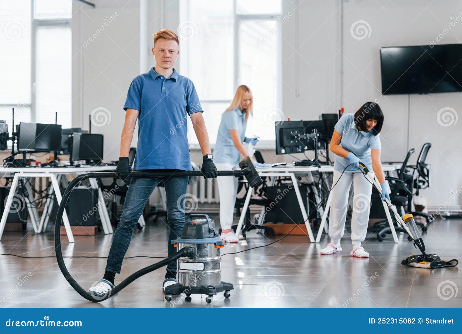Guy with Vacuum Cleaner. Group of Workers Clean Modern Office Together ...