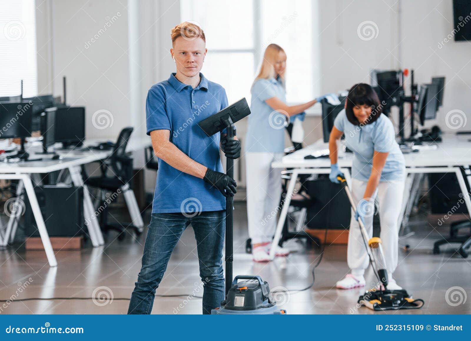 Guy with Vacuum Cleaner. Group of Workers Clean Modern Office Together ...