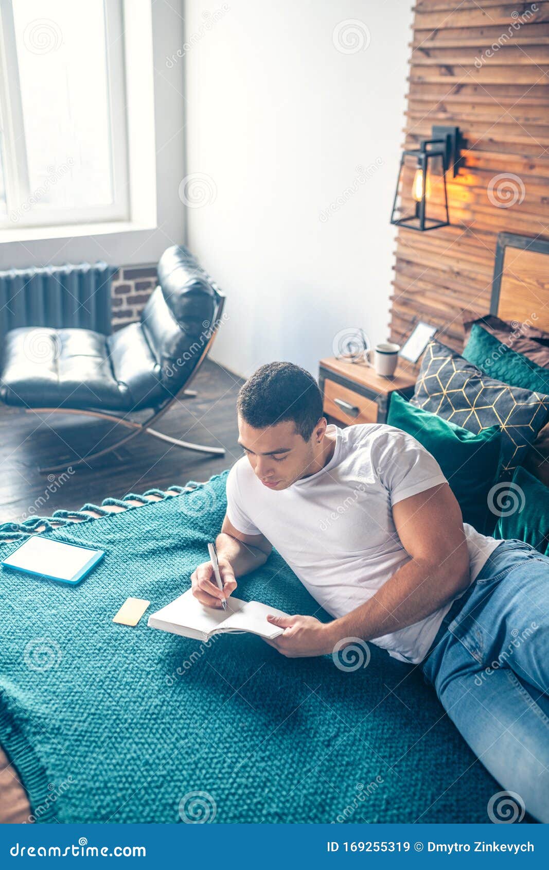 Guy Writing with a Pen in Notebook Lying on the Bed. Stock Image ...