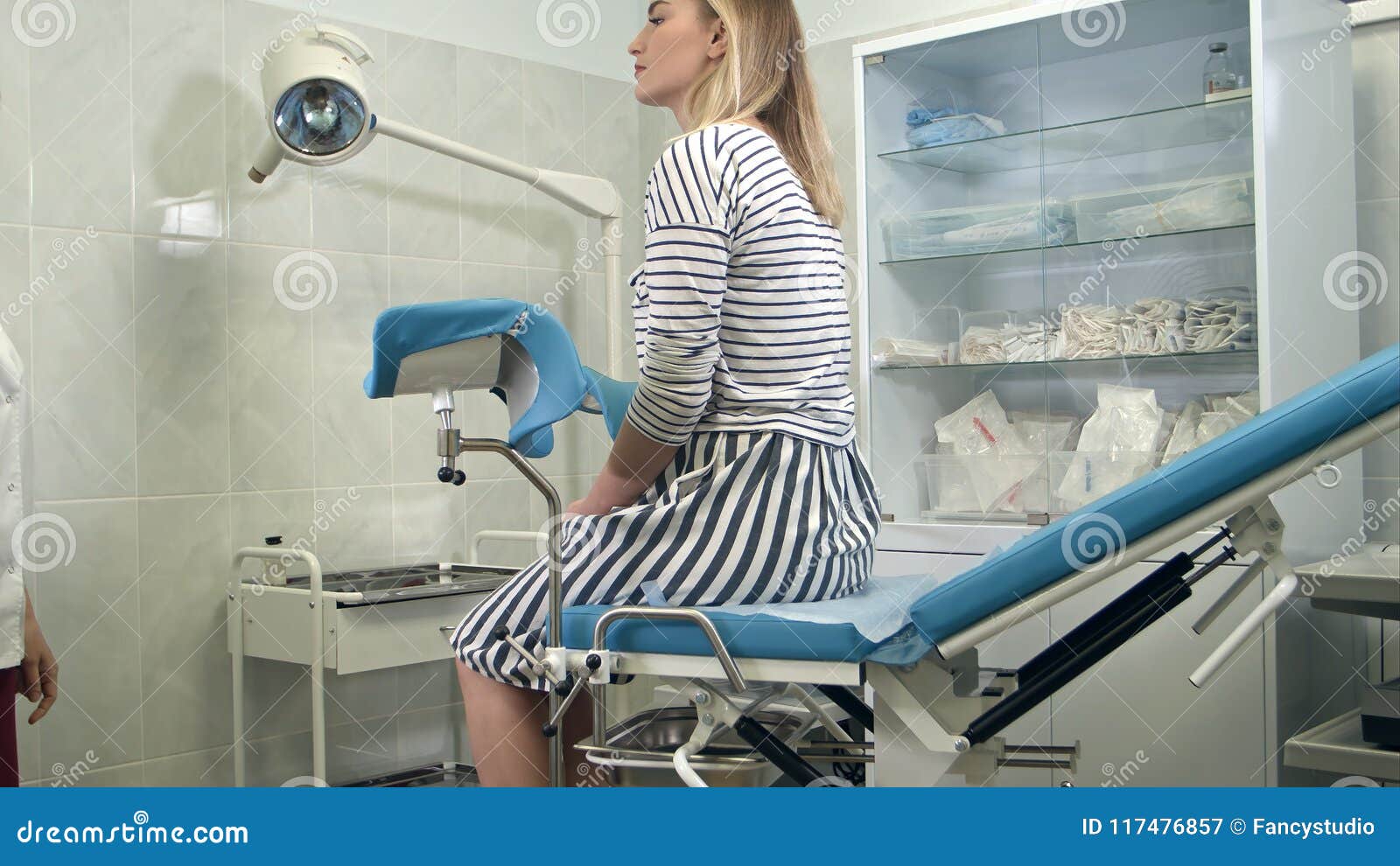 Gynecologist Asking Female Patient To Sit On Gynecological Chair For