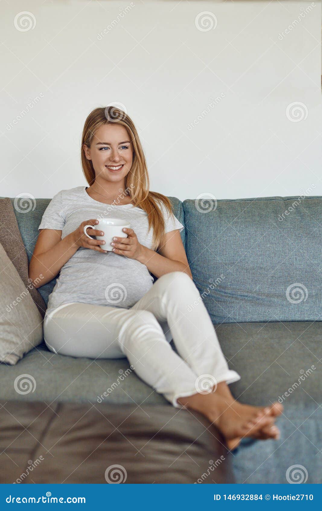 Pretty Barefoot Young Pregnant Woman Relaxing On A Couch Stockfoto