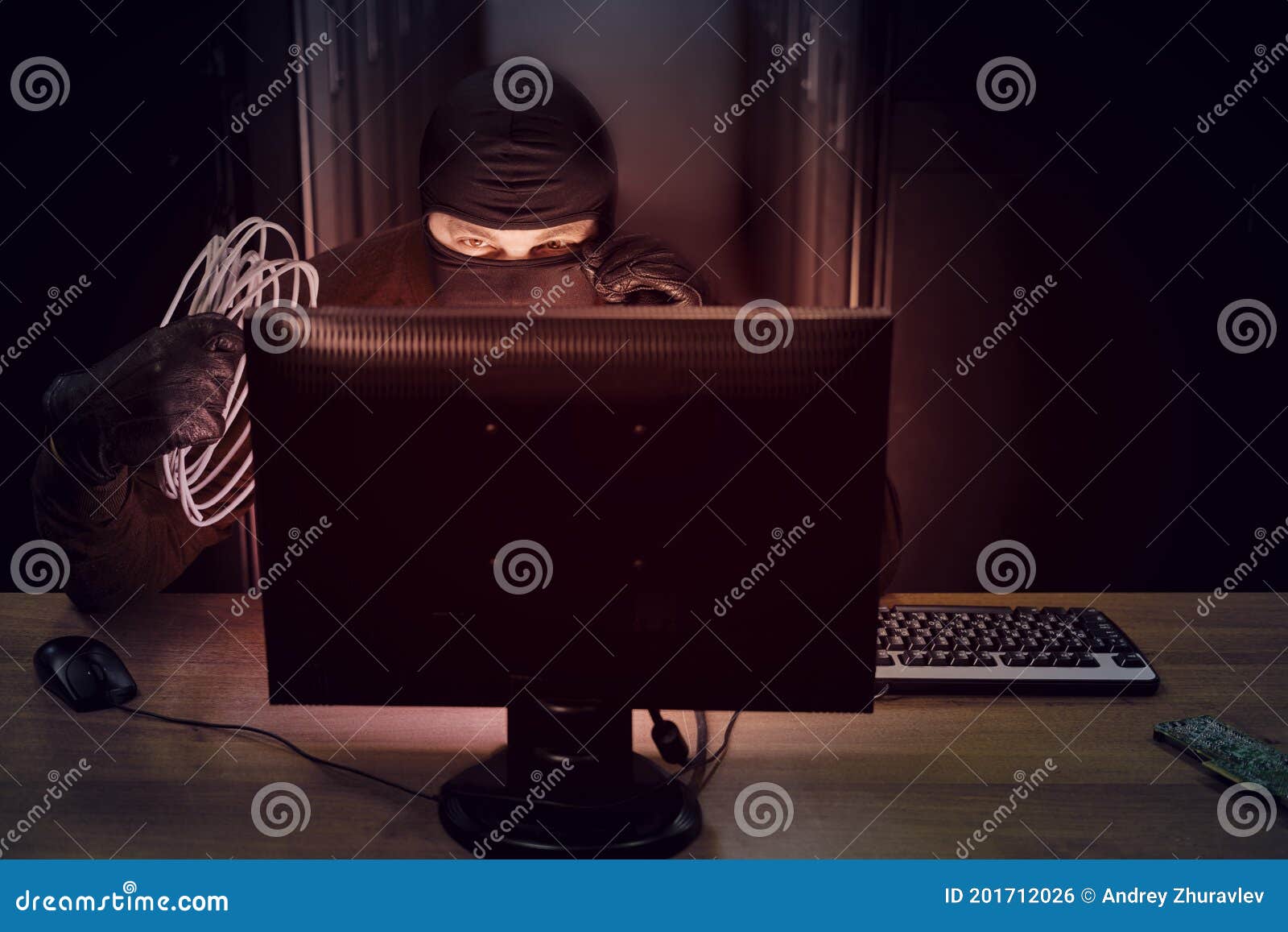 A Hacker in a Black Mask with Wires in His Hand in a Server Room ...