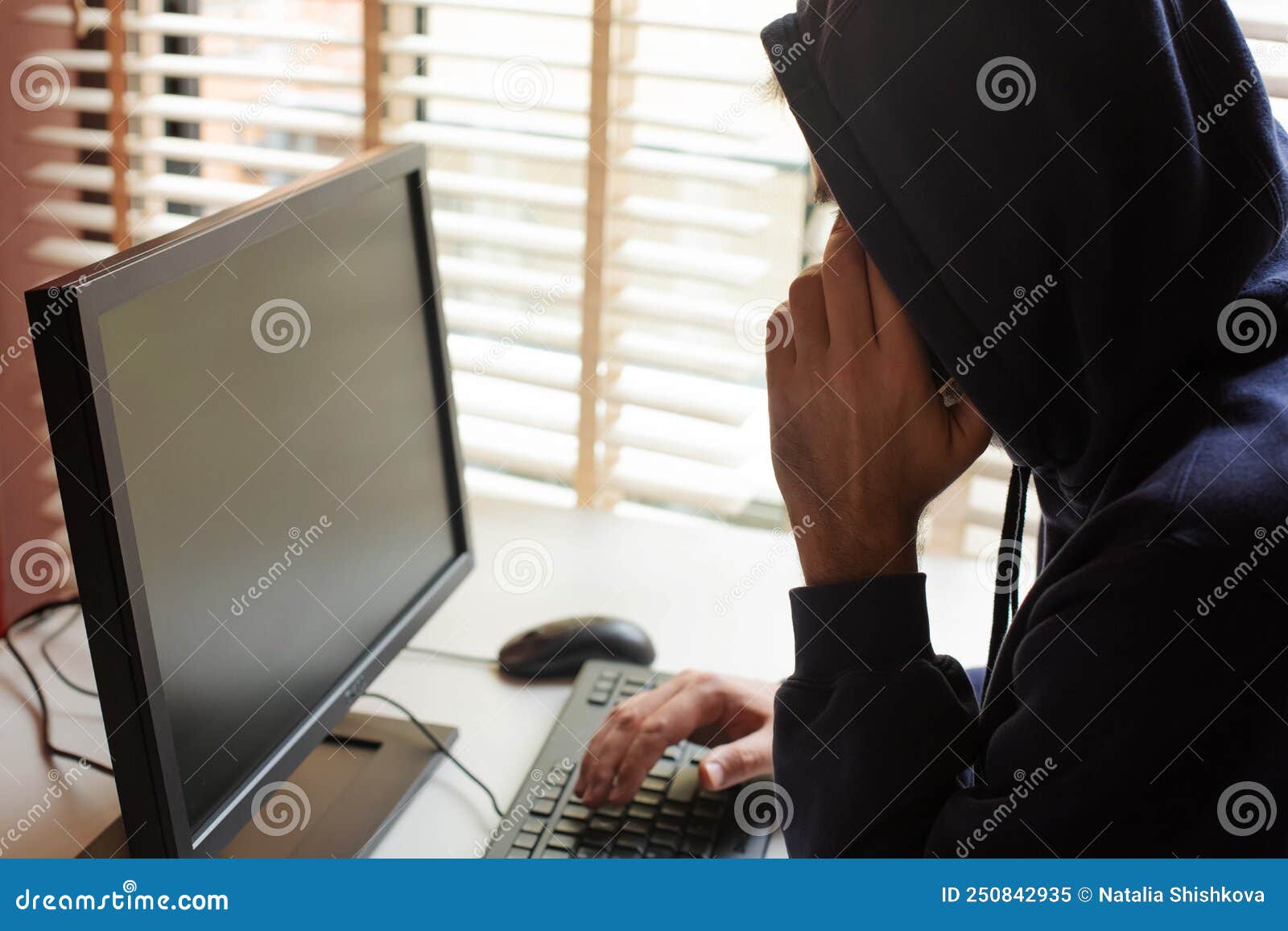 A Hacker in a Hooded Sweatshirt with a Hidden Face Typing on a Computer ...