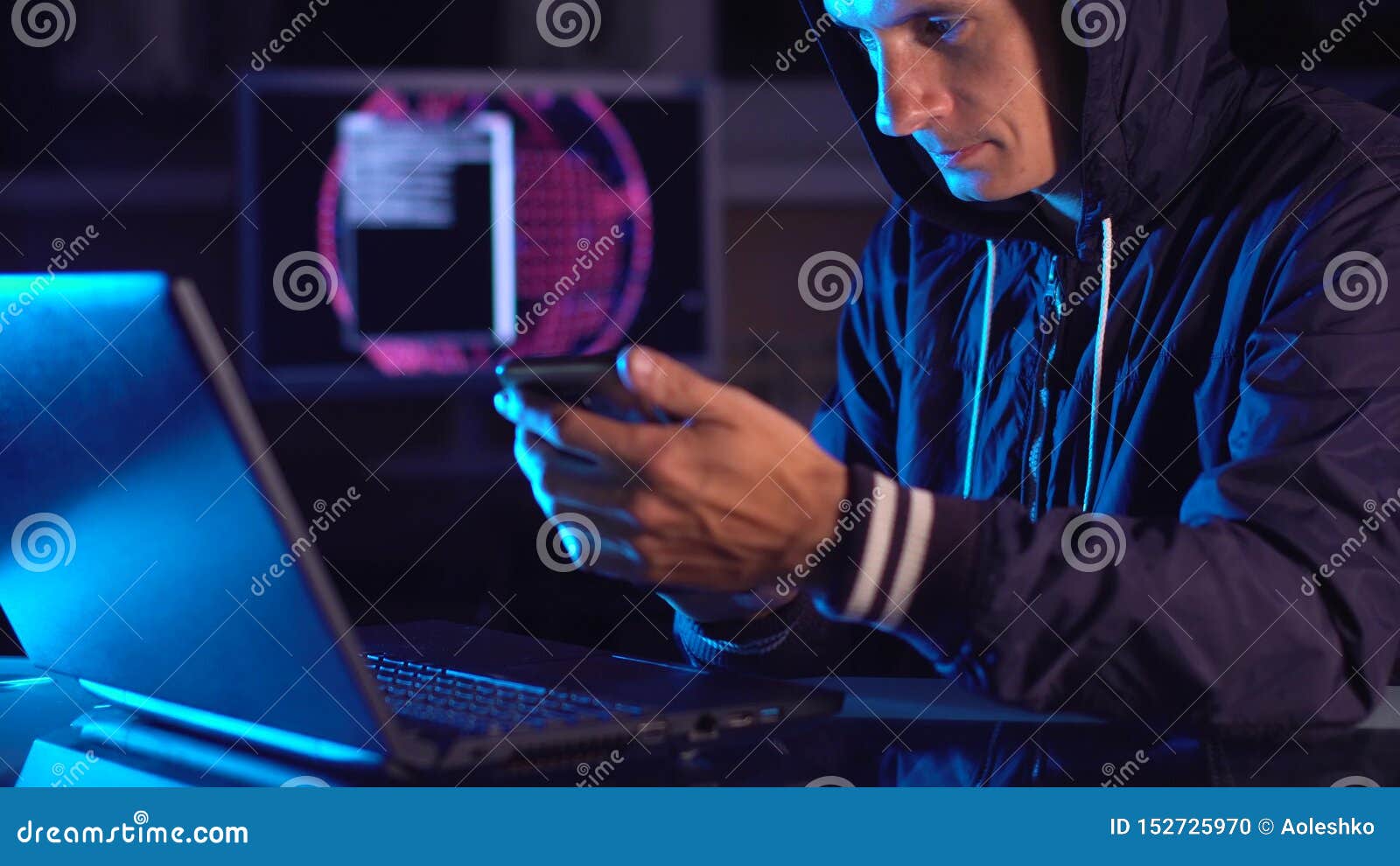 Hacker in the Hood Holding the Phone in His Hands Trying To Hack the ...