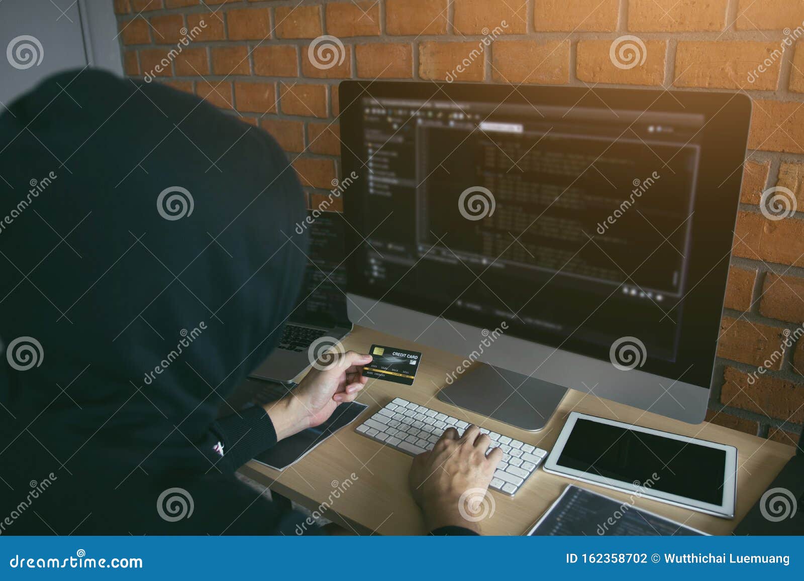 Hacker in the Hood Working with Computer and Holding Credit Card with ...