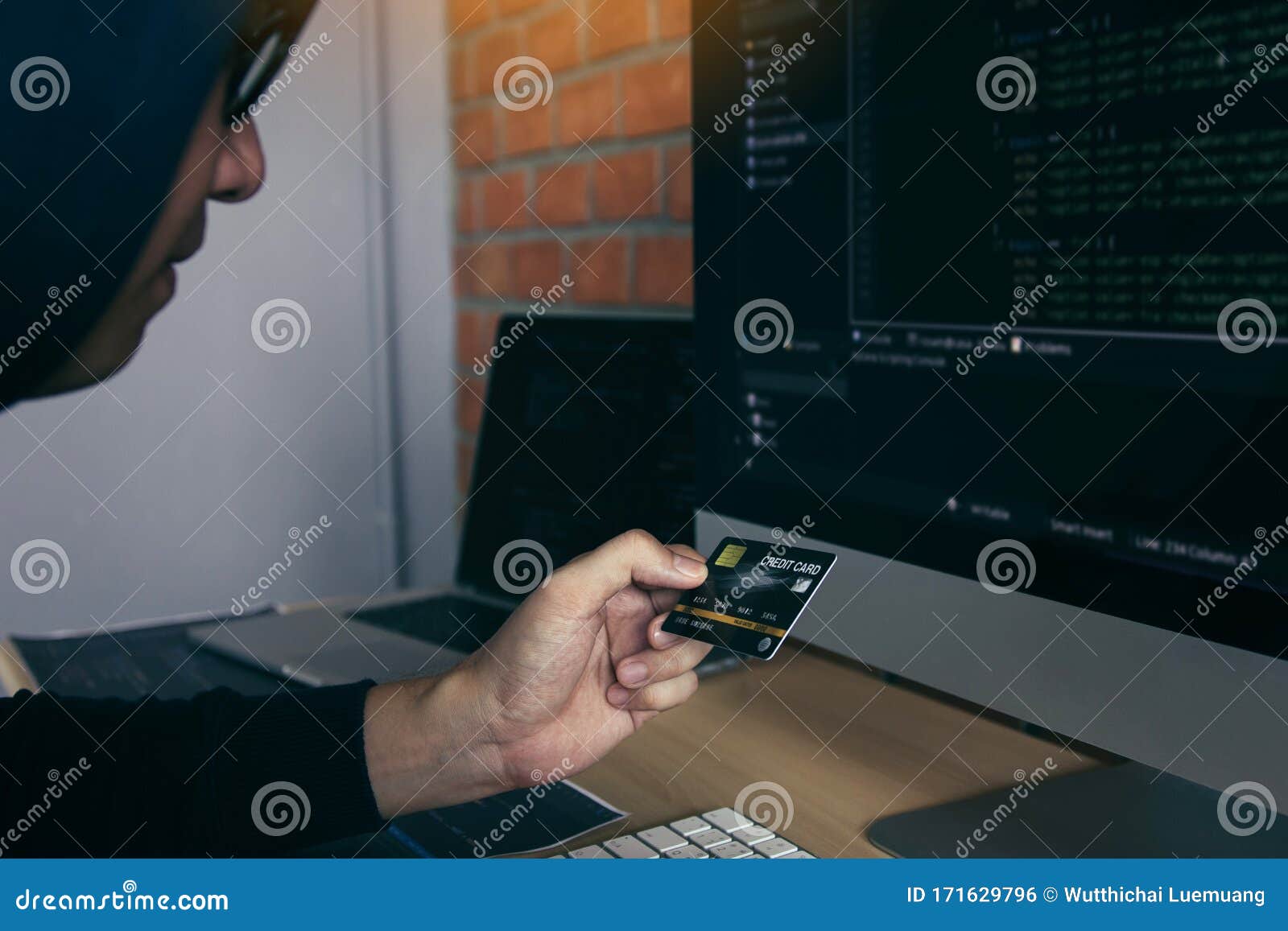 Hacker in the Hood Working with Computer and Holding Credit Card with ...