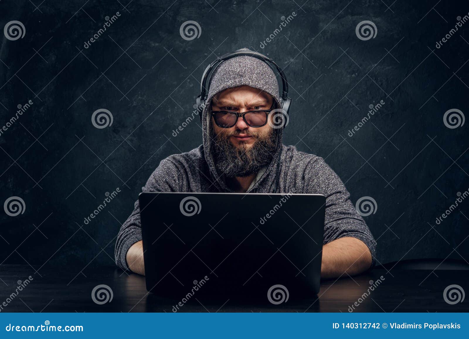 A Hacker Sits Behind a Laptop in a Dark Office and Stares Intently at ...