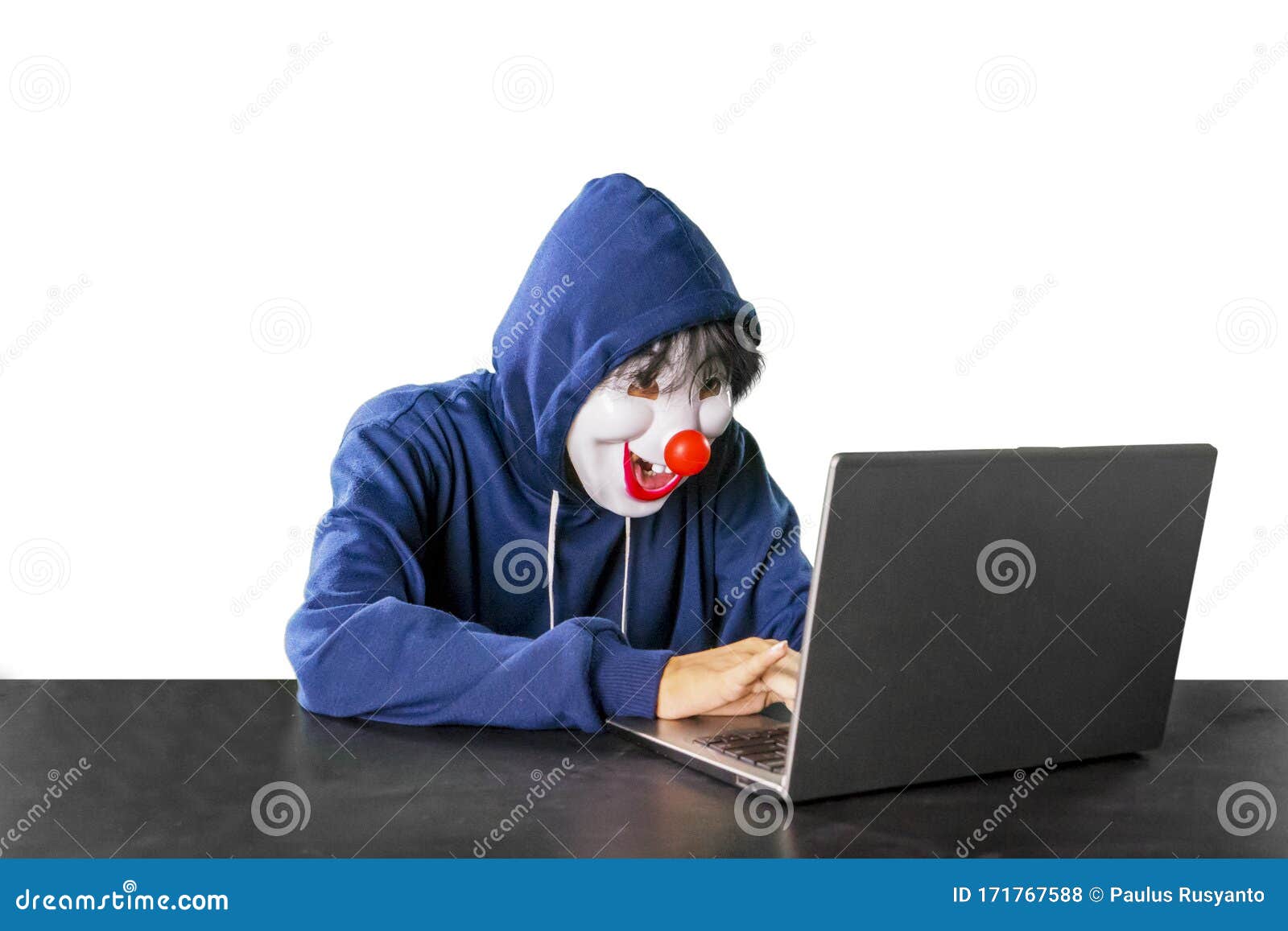 Hacker Wearing Clown Mask Using a Laptop Computer with White Background ...