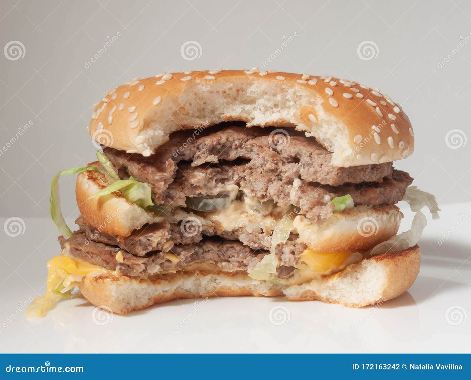 Half-eaten Burger with Two Cutlets on a White Plate and a Light ...