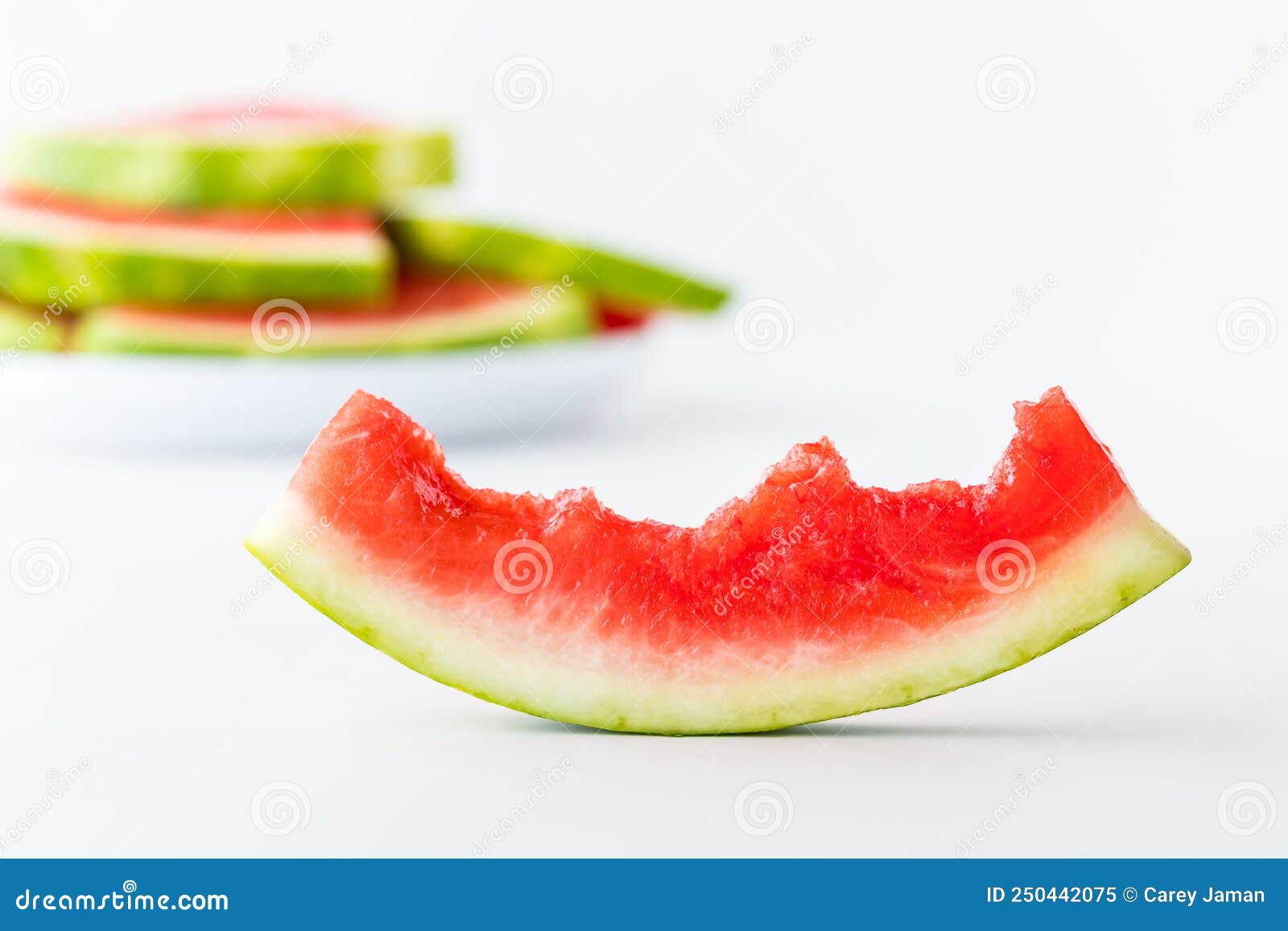 A Half Eaten Slice of Watermelon with a Pile of Watermelon Slices in ...
