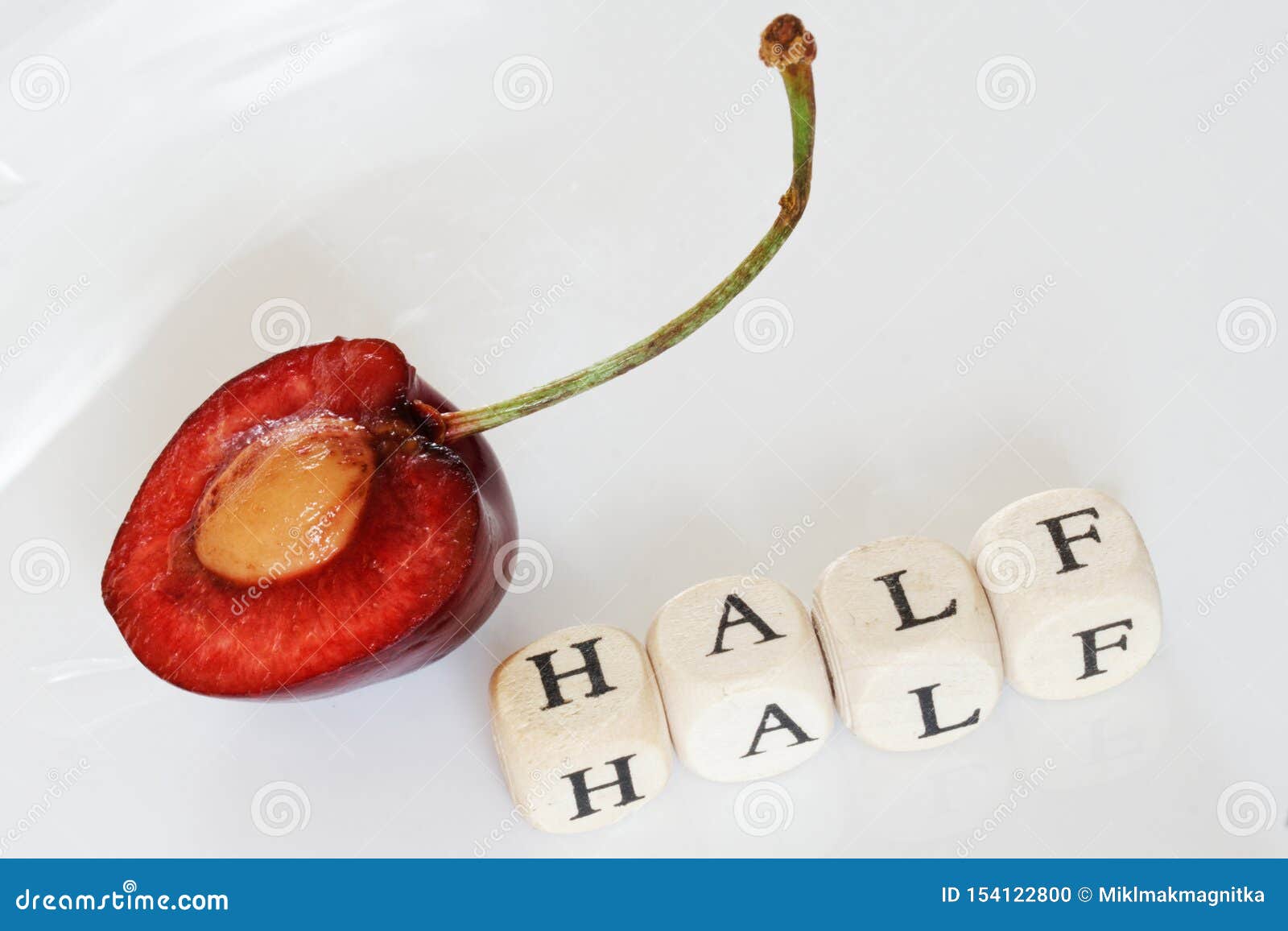 A Half of Red Sweet Cherry on a Light Background Next To the Cubes with ...