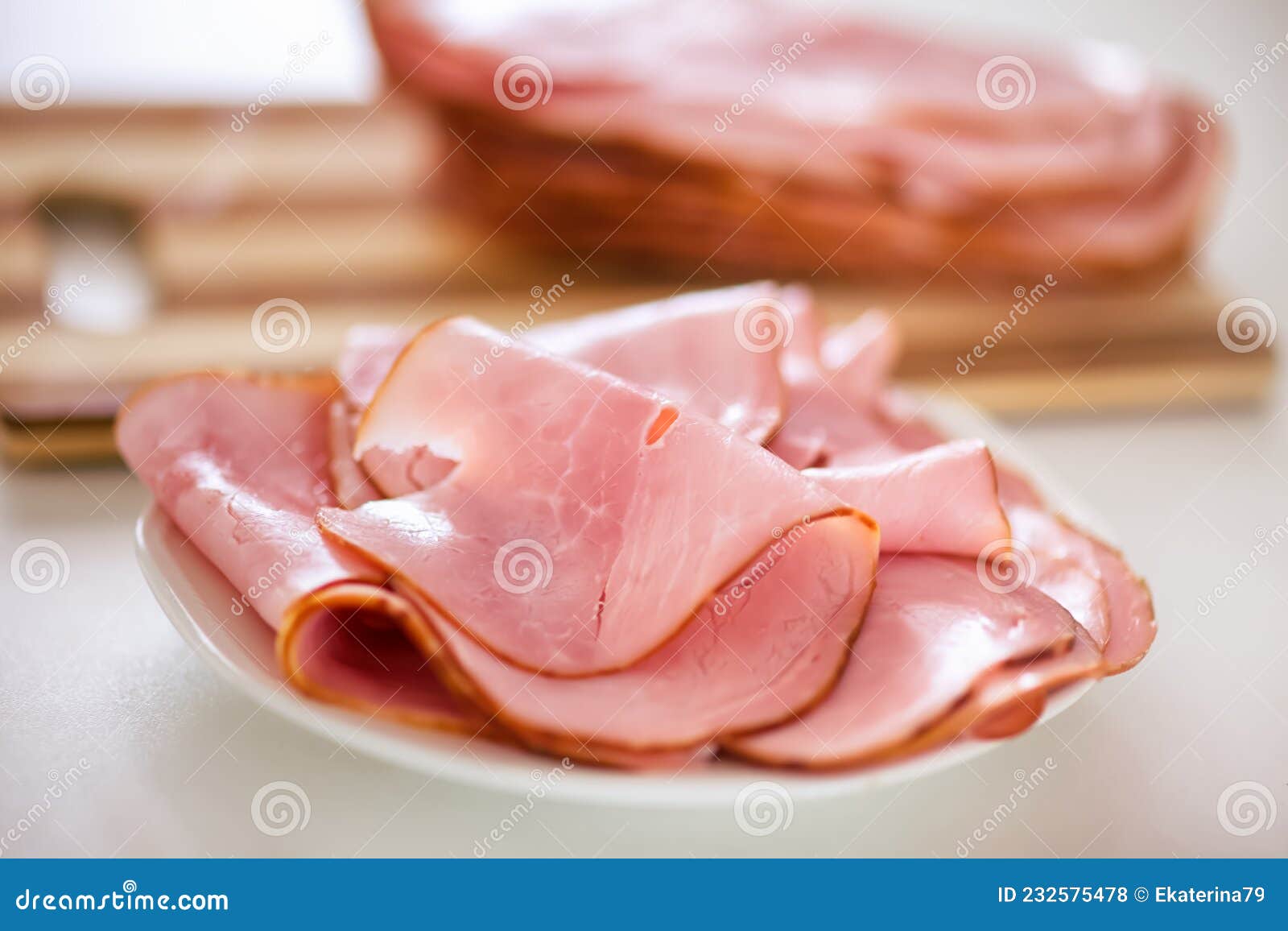 Ham Slices on White Plate with a Chopping Board with a Stack of Ham in ...