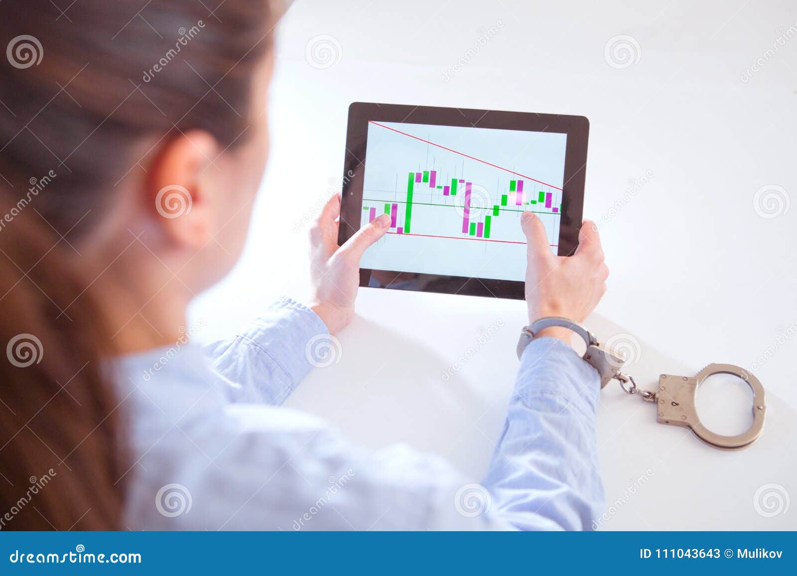 Hand Attached with Handcuffs and Tablet with a Financial Graph on the ...