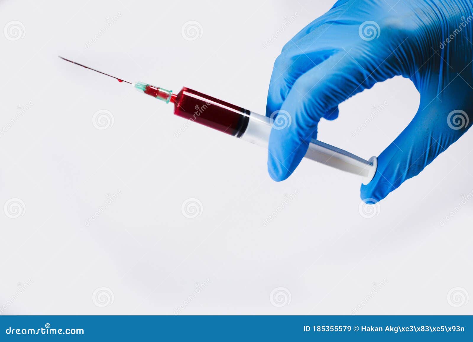 Hand with Blue Nitrile Glove is Holding Syringe with Red Liquid, in ...