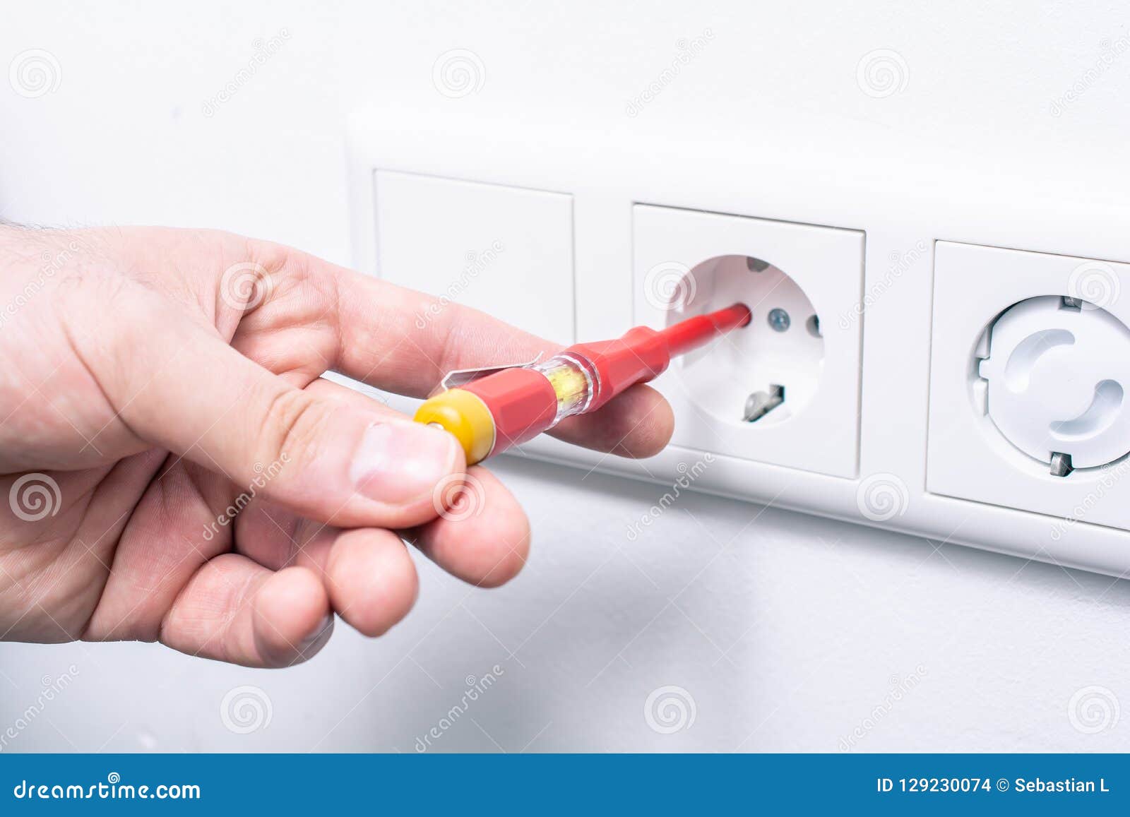 The Hand of an Electrician Holding a Phase Tester in a Wall Socket, the ...