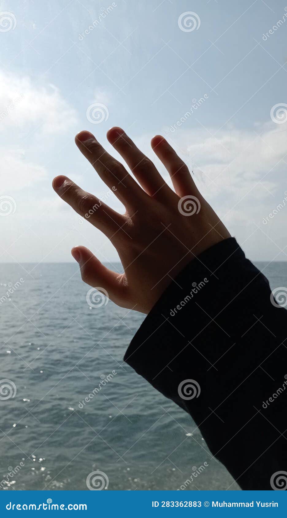 A hand facing the blue sea stock image. Image of active - 283362883
