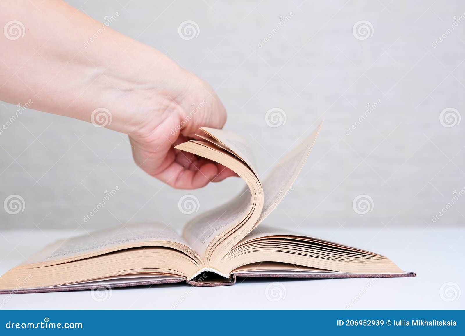 A Hand Flipping Pages of a Book Lying on a Table, Reading Books Hobby ...