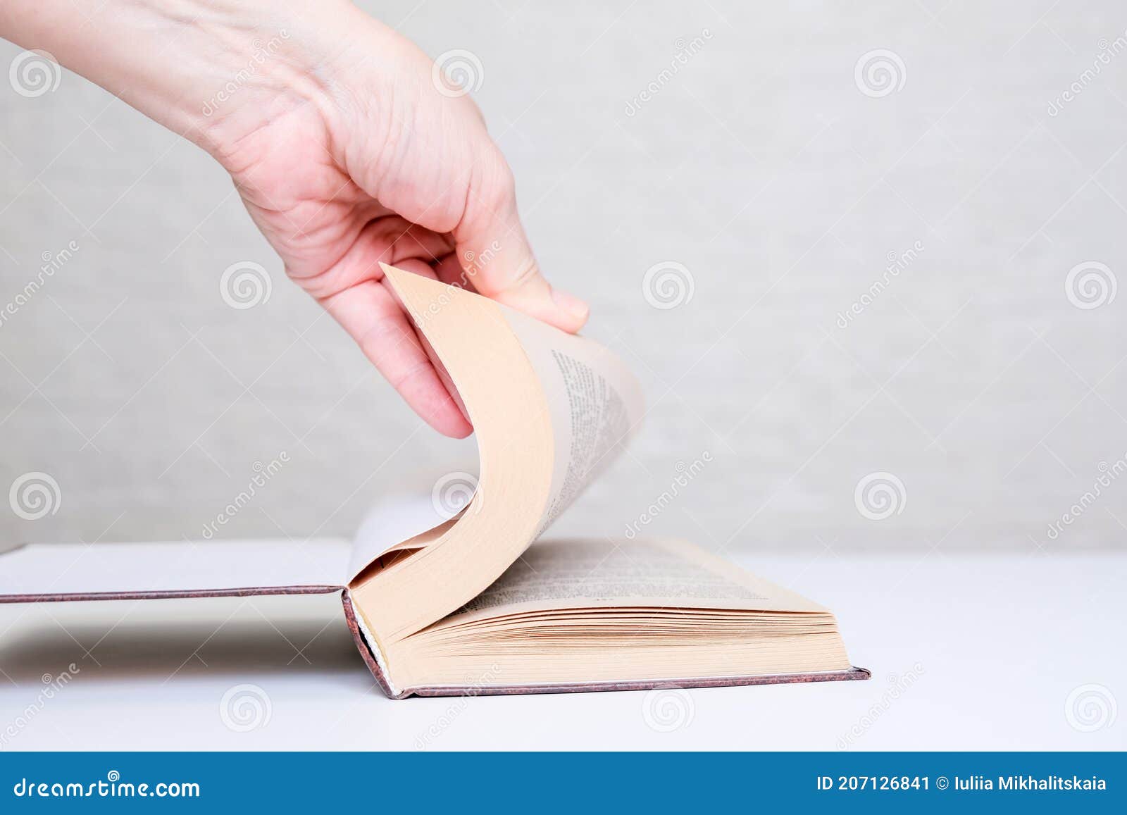 A Hand Flipping Pages of a Book Lying on a Table, Reading Books Hobby ...