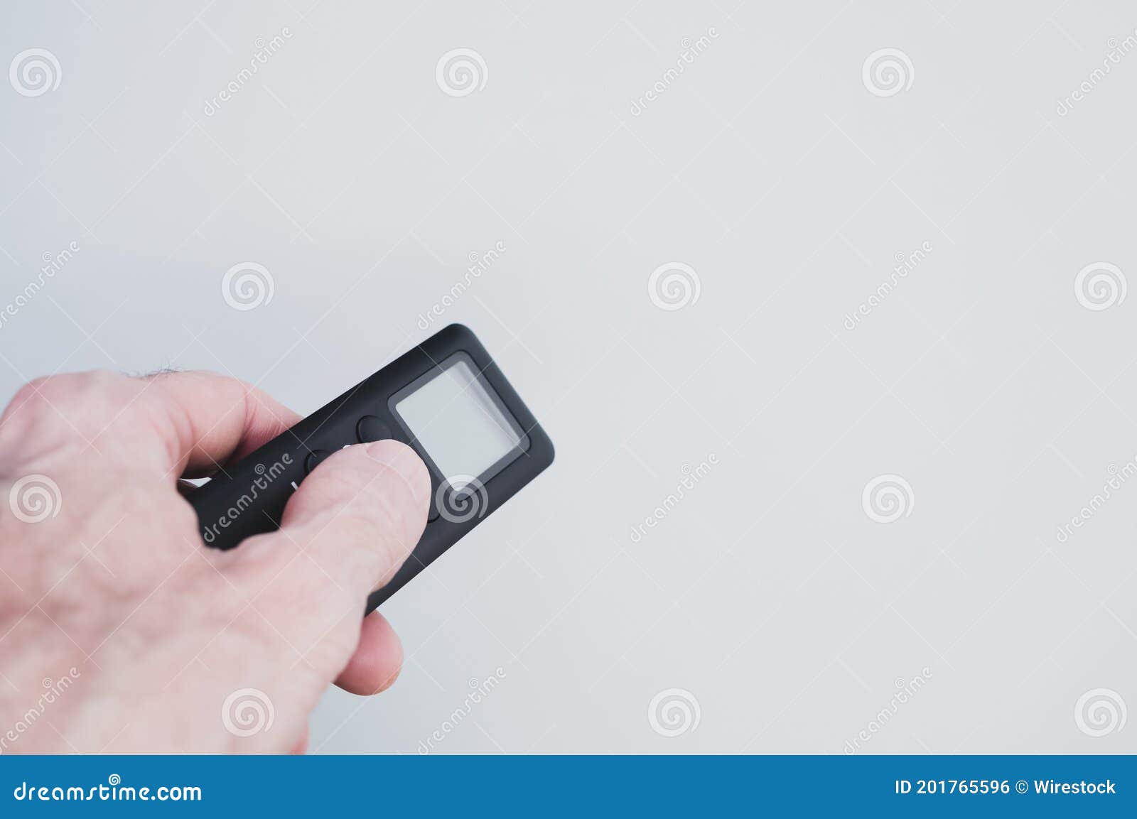 Hand Holding a Black Remote Controller on Gray Background for a Copy ...