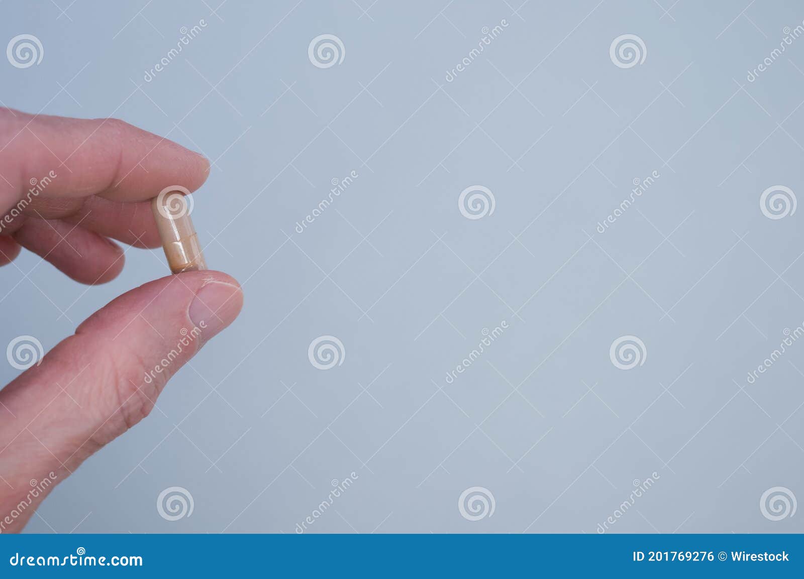 Hand Holding a Capsule on Gray Background with a Copy Space Stock Photo ...