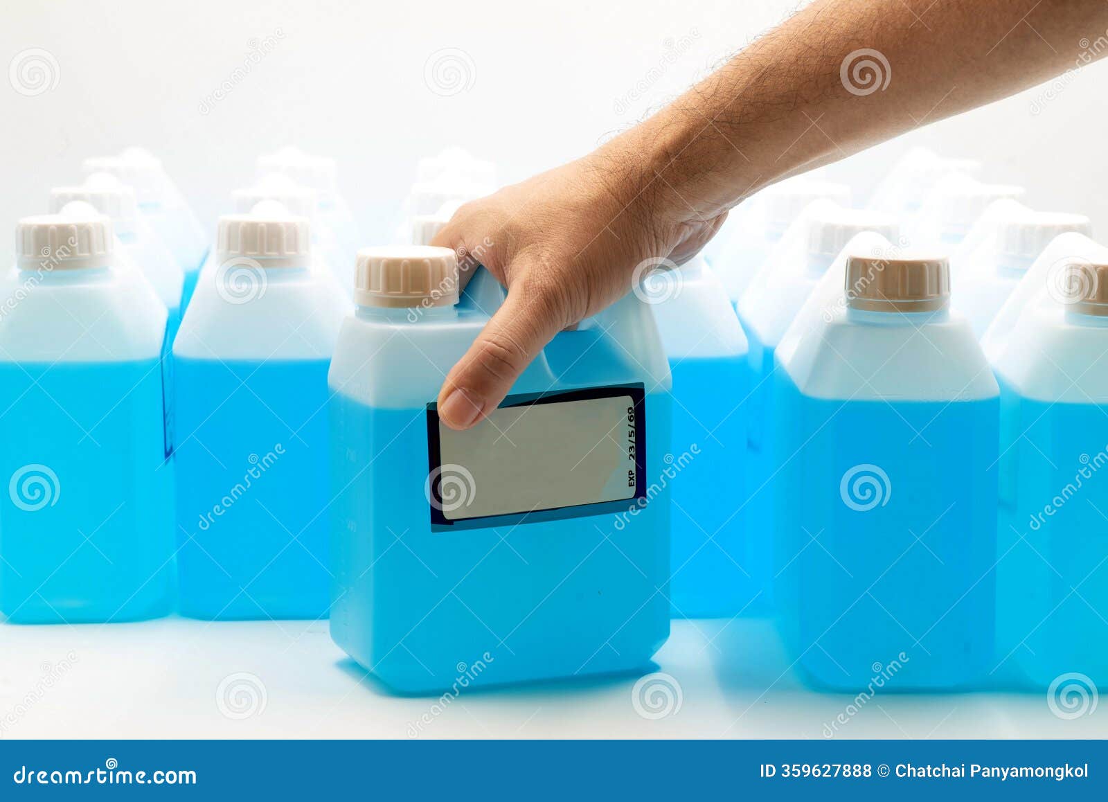 Hand Holding a Container of Blue Ethyl Alcohol among Multiple Liquid ...