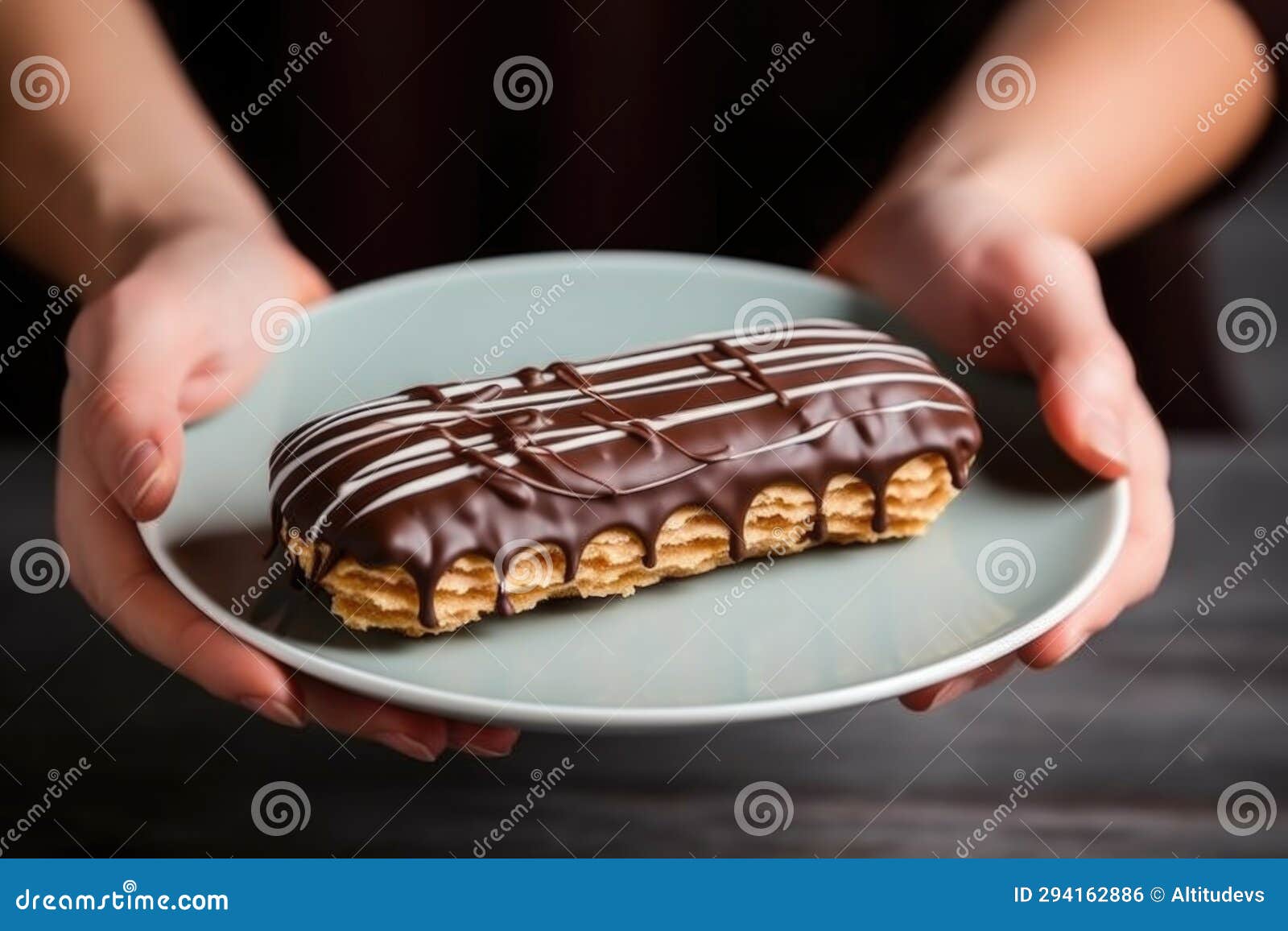 Hand Holding an Eclair Topped with Thin, Zigzag Chocolate Stripes on a ...