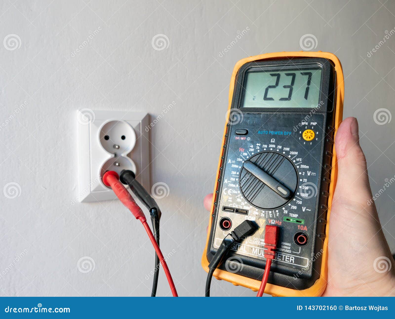 Hand Holding an Electric Multimeter in Front of the Electric Socket ...