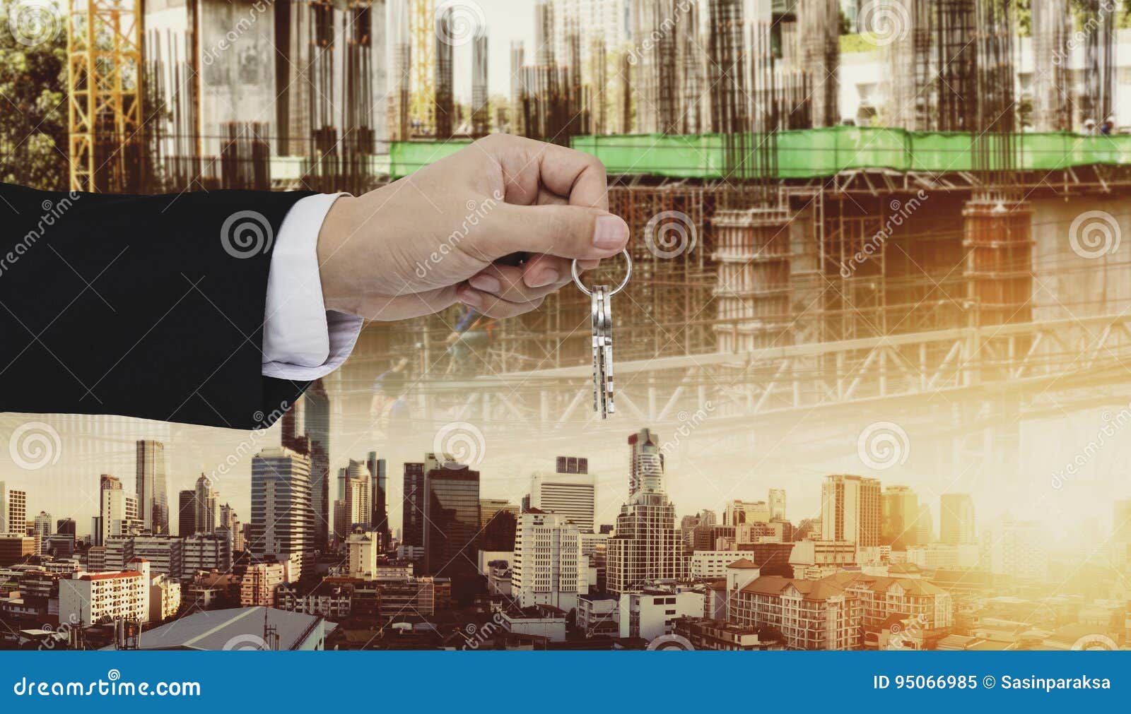 Hand Holding Keys, with Site Construction and City in Sunset Background ...
