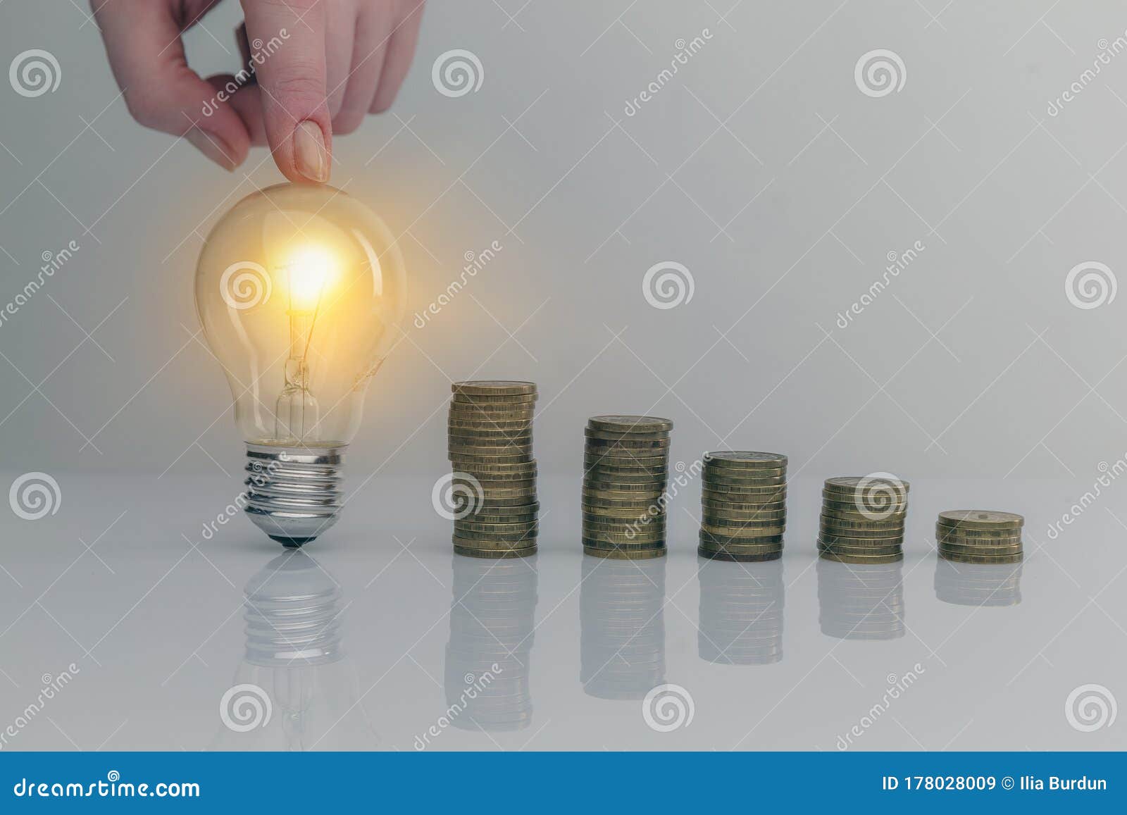 Hand Holding a Light Bulb with Coins Stack. Creative Ideas for Saving ...