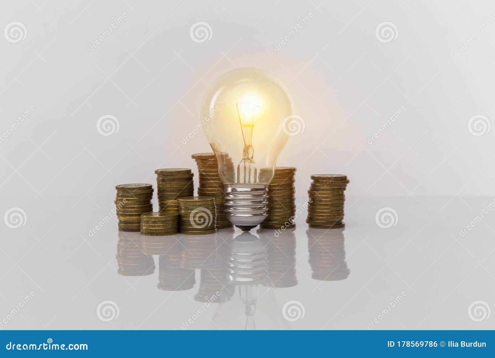 Hand Holding a Light Bulb with Coins Stack. Creative Ideas for Saving ...
