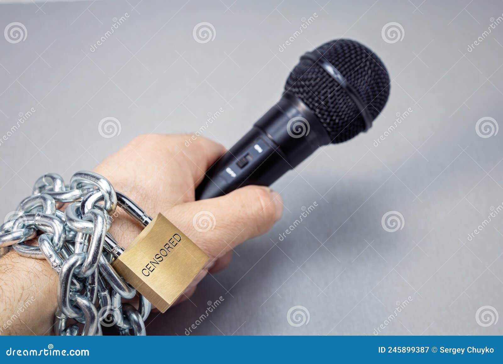 Hand Holding Microphone Tied with Chains and Lock on Grey Surface ...