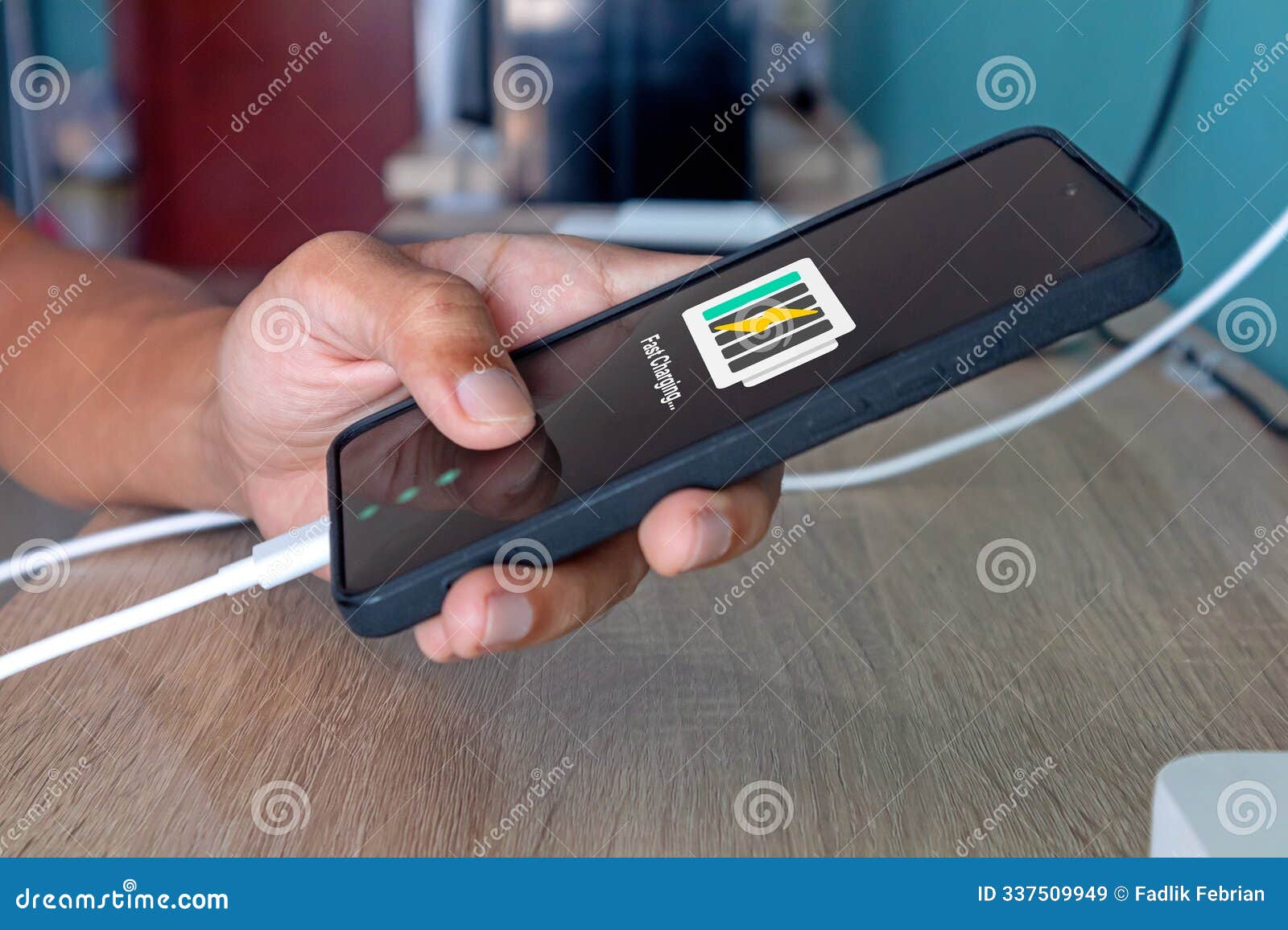 Hand Holding a Mobile Phone while Charging the Battery from Wall Outlet ...