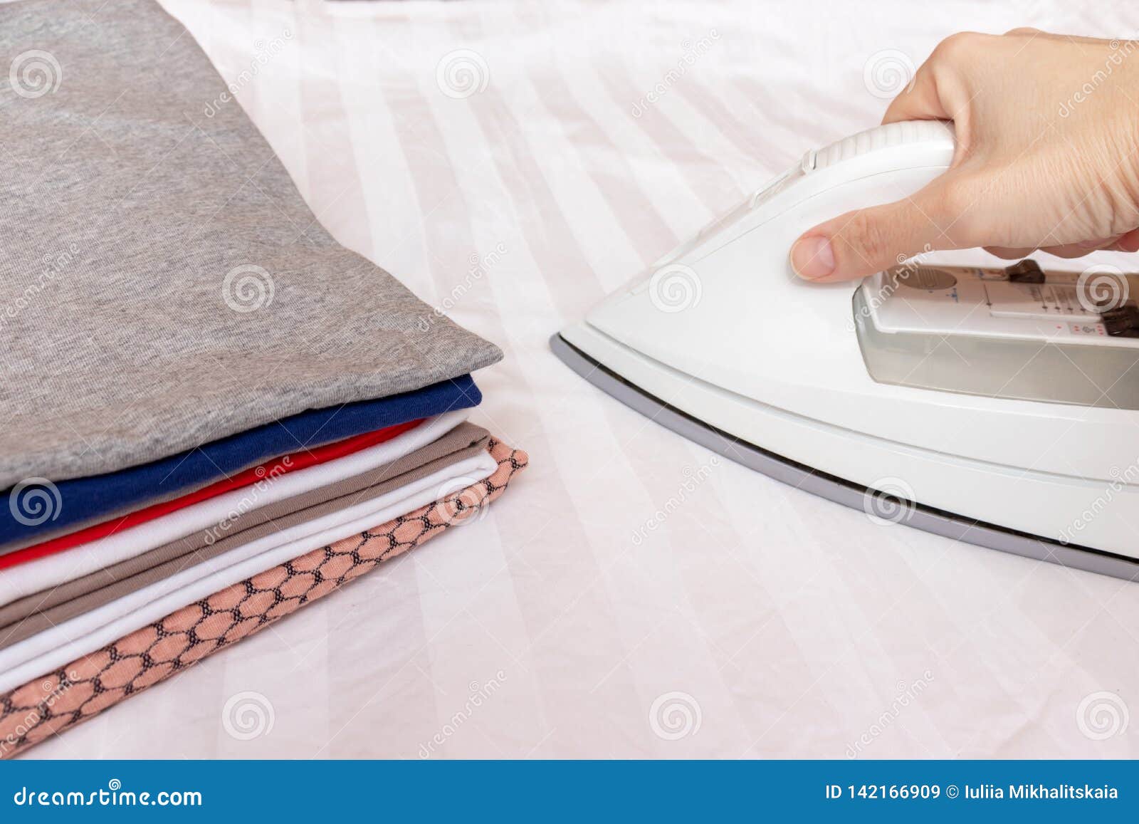 A Hand Holding Modern Electrical White Iron Ready To Iron a Stack of ...
