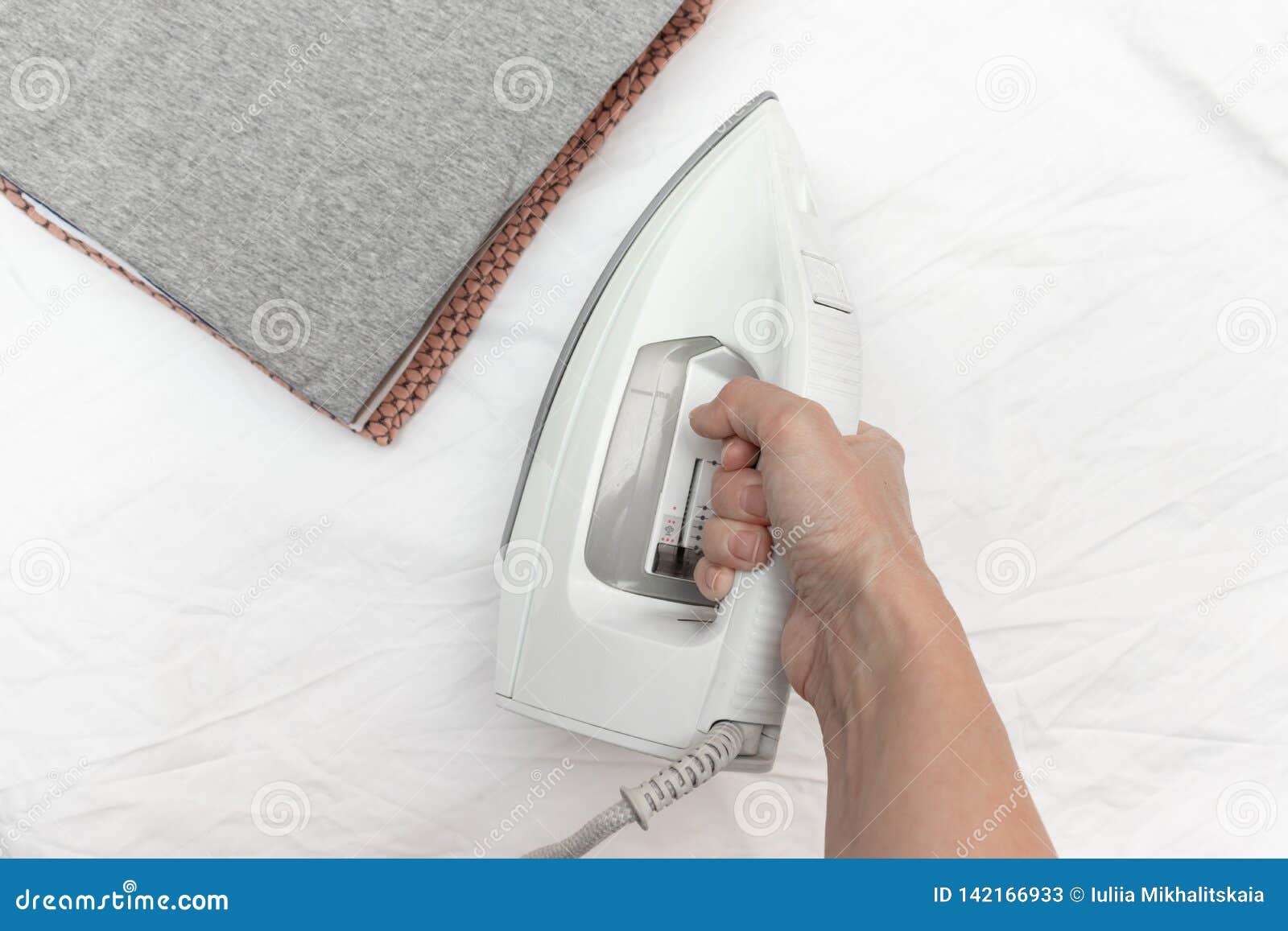 A Hand Holding Modern Electrical White Iron Ready To Iron a Stack of ...