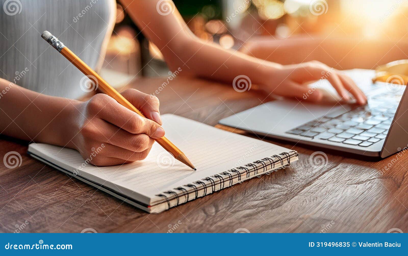 Hand Holding a Pencil Over a Notebook with Blurred Laptop Background ...