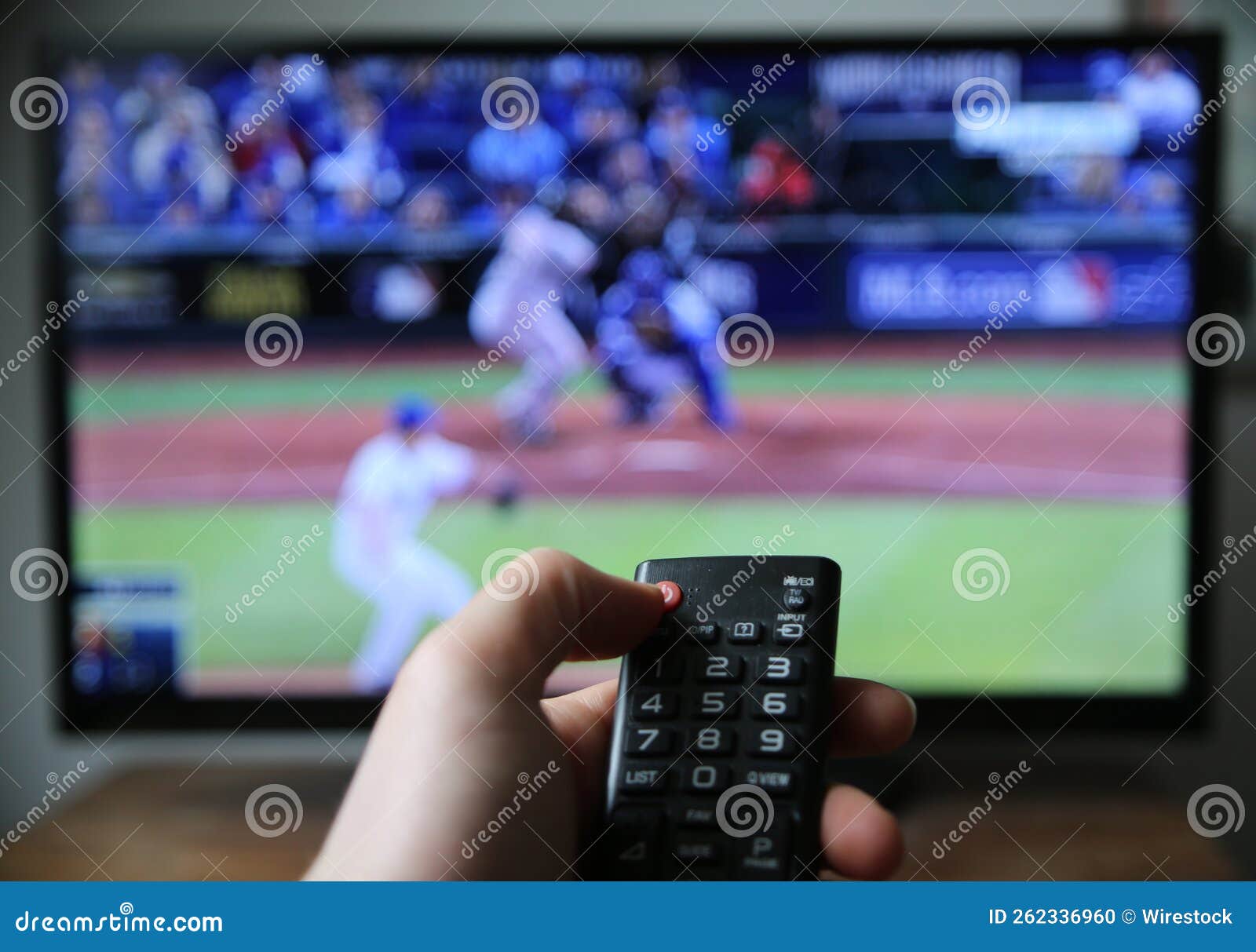 Hand Holding the Remote Controller Against the Blurred TV Screen ...