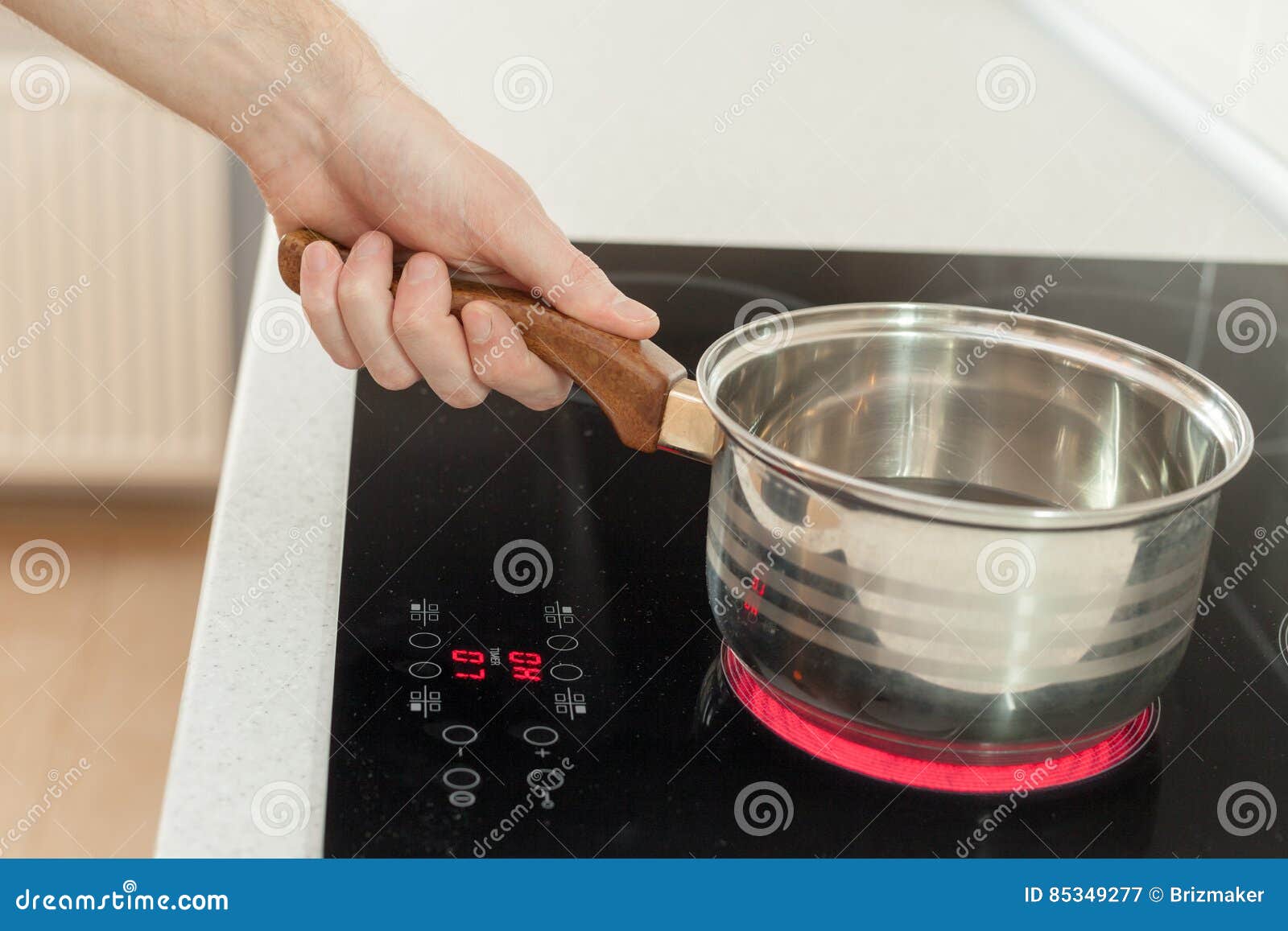 Hand Holding a Saucepan in Modern Kitchen with Induction Stove. Stock ...