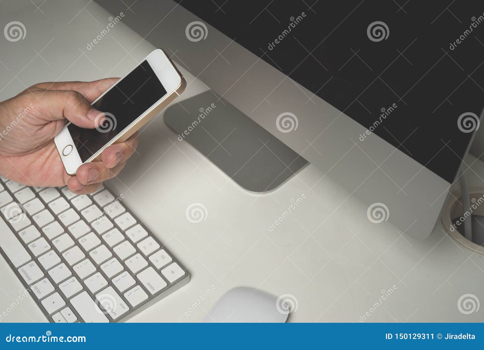 Hand Holding Smart Phone on White Desk with Computer Desktop with White ...
