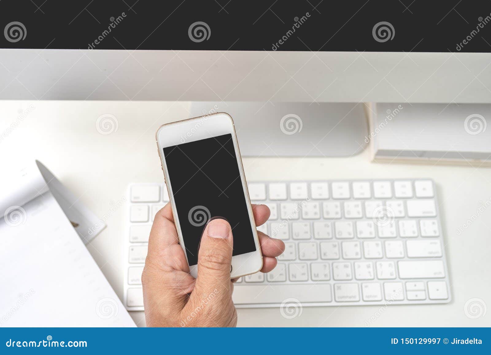 Hand Holding Smart Phone on White Desk with Computer Desktop with White ...