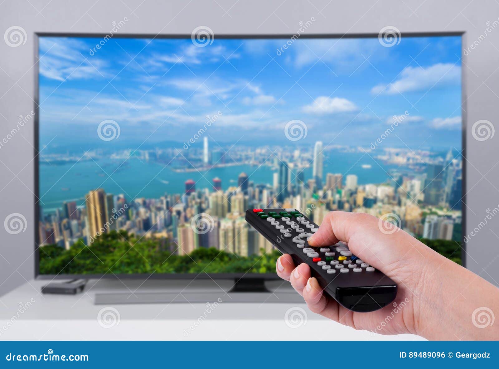 Hand Holding TV Remote Control with a Television and City Screen Stock ...