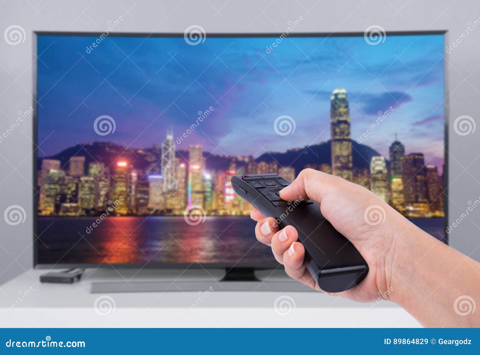 Hand Holding TV Remote Control with a Television and City Screen Stock ...