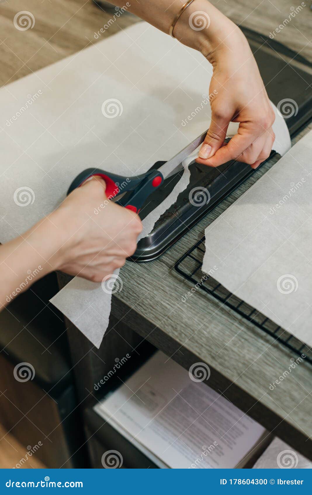 Hand Holding Up a Sheet of Baking Paper and Cut Using a Pair of ...