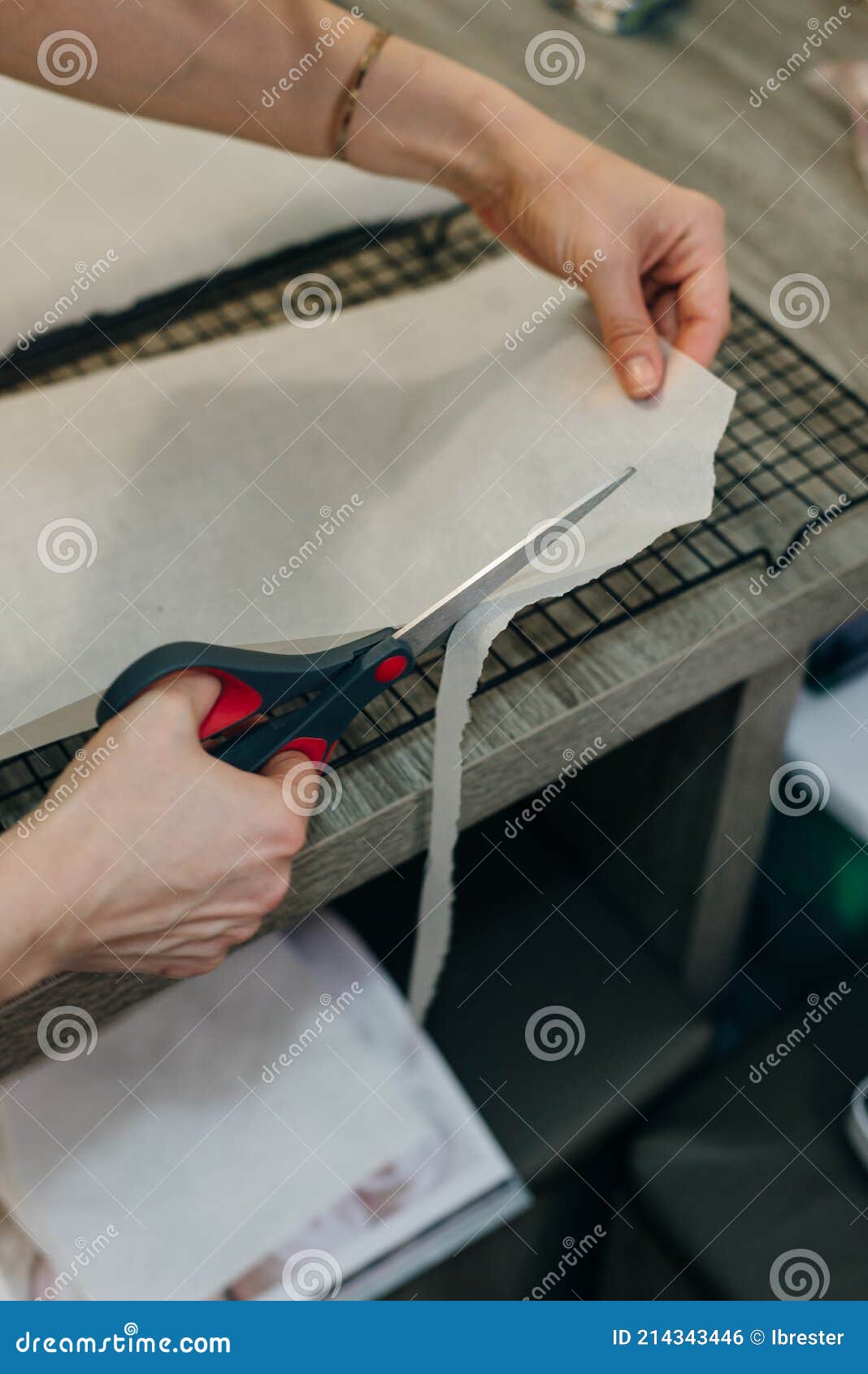 Hand Holding Up a Sheet of Baking Paper and Cut Using a Pair of ...
