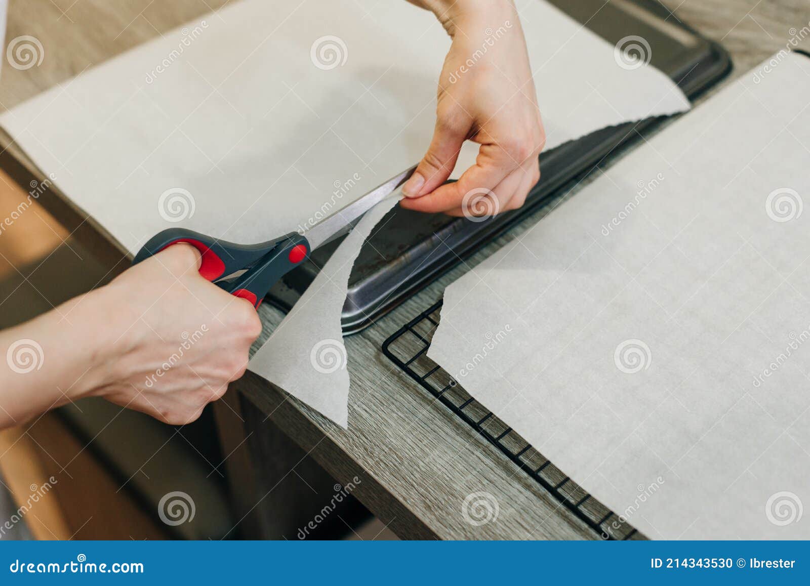 Hand Holding Up a Sheet of Baking Paper and Cut Using a Pair of ...