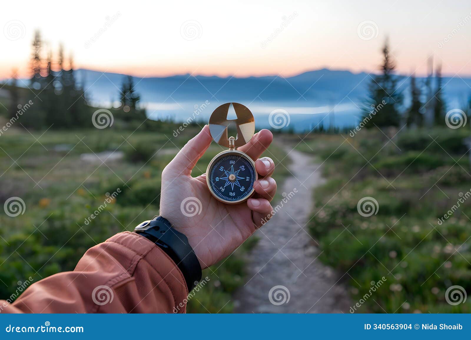 Hand Holds Compass, Pointing To Trail through Greenery and Distant ...