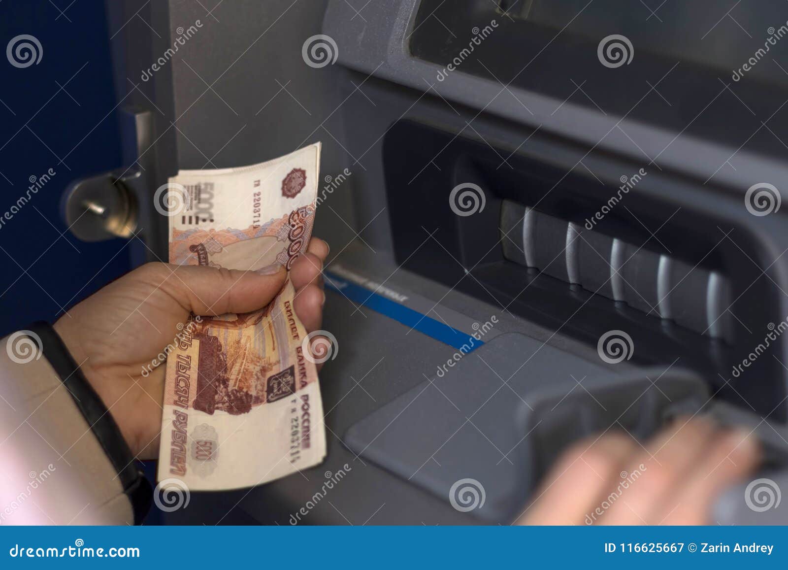 The Hand Holds a Stack of Money in Front of the ATM Receiver Stock ...